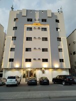 Um hotel de vários andares com fachada moderna, unidades de ar condicionado e entrada com portão.