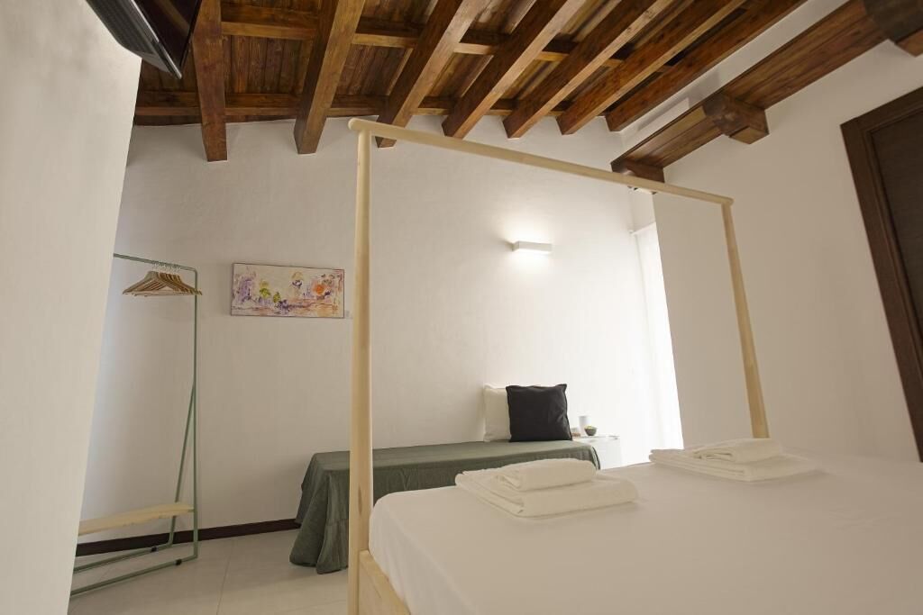 Um quarto com uma cama de dossel, uma mesa de cabeceira e uma prateleira na parede.
