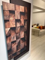 Uma sala de estar moderna com uma obra de arte na parede com padrão geométrico, um sofá com almofadas e uma mesa de centro.