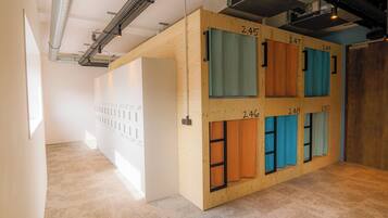 Quarto de hotel moderno com divisória de madeira, janelas numeradas e porta visível.
