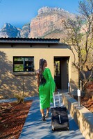 Uma pessoa de vestido verde caminhando por um caminho em direção a um edifício com uma janela exibindo informações.