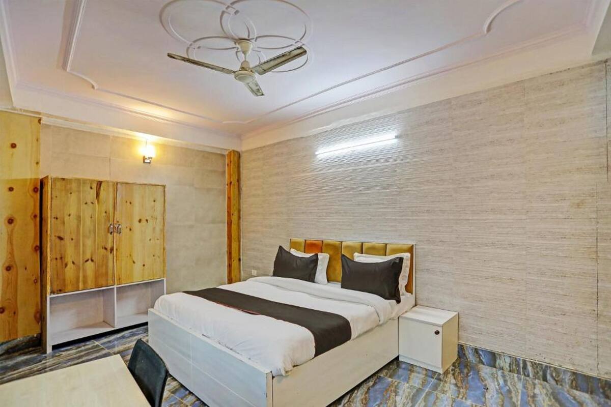 Um quarto com cama, mesas de cabeceira, guarda-roupa e ventoinha no teto.