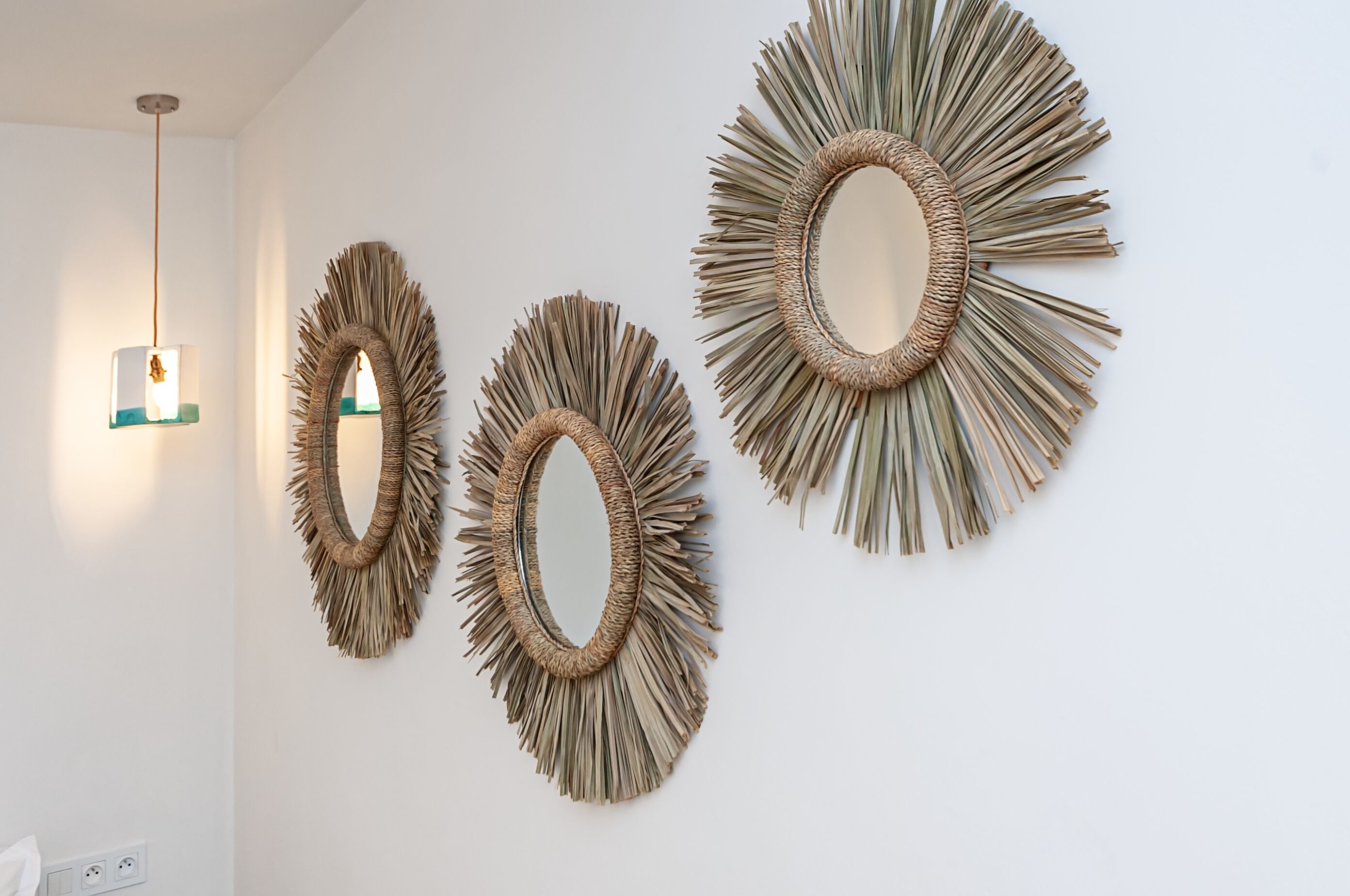 Três espelhos fixados na parede, com um padrão natural trançado.