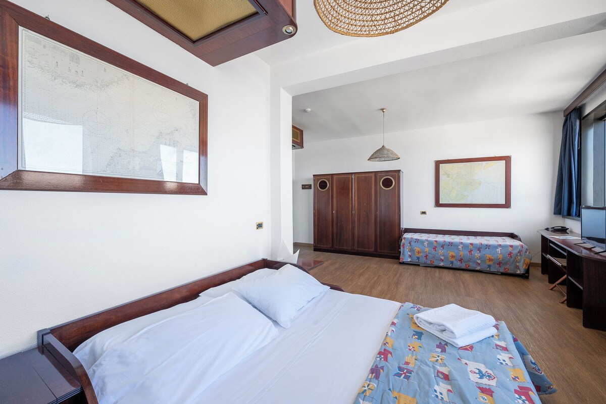 Quarto com cama, escrivaninha, guarda-roupa e mapa na parede.