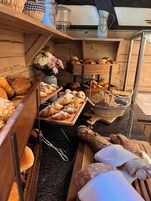 Um buffet de café da manhã com pães, doces e flores variados.