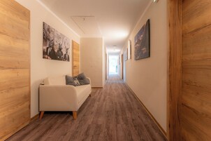 Um corredor com piso de madeira, um sofá branco com almofada e duas obras de arte emolduradas nas paredes.