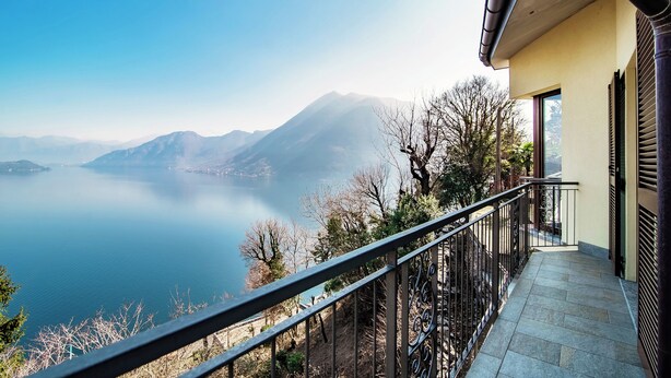 Uma varanda com vista para um lago e montanhas.