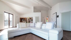Uma sala de estar moderna com um sofá branco modular, piso de madeira, uma estante embutida e um radiador.