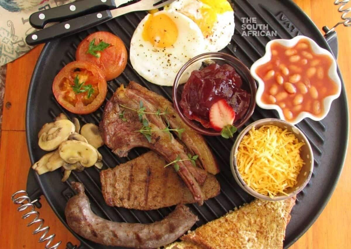 Prato de café da manhã com ovos, bacon, salsichas, cogumelos, tomates e acompanhamentos.