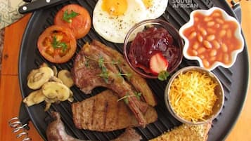Prato de café da manhã com ovos, bacon, salsichas, cogumelos, tomates e acompanhamentos.
