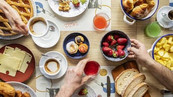 Uma mesa com diversos itens de pequeno-almoço, incluindo pastelaria, fruta e bebidas.