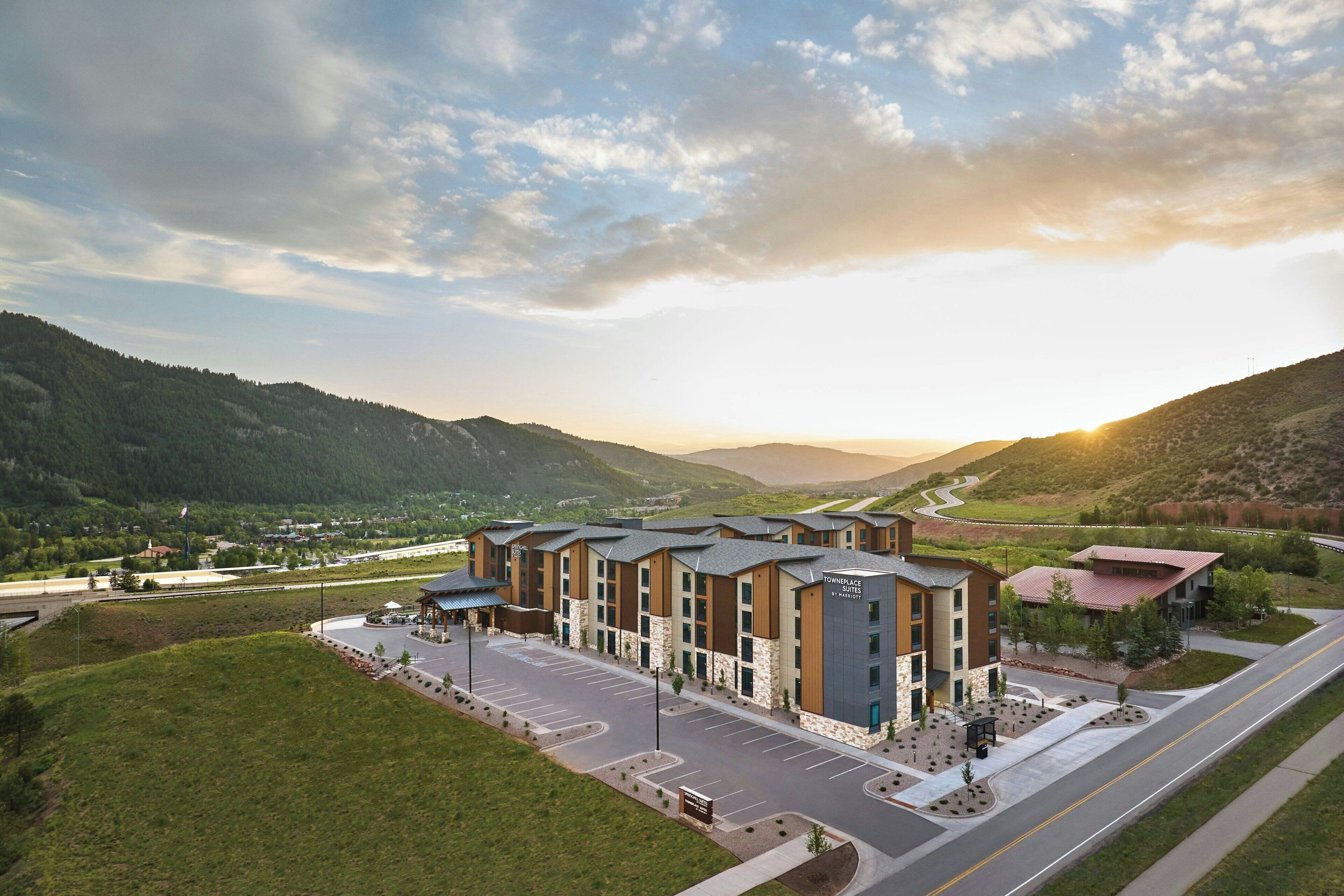 Hotel moderno com um pátio central, rodeado por vegetação exuberante e montanhas.