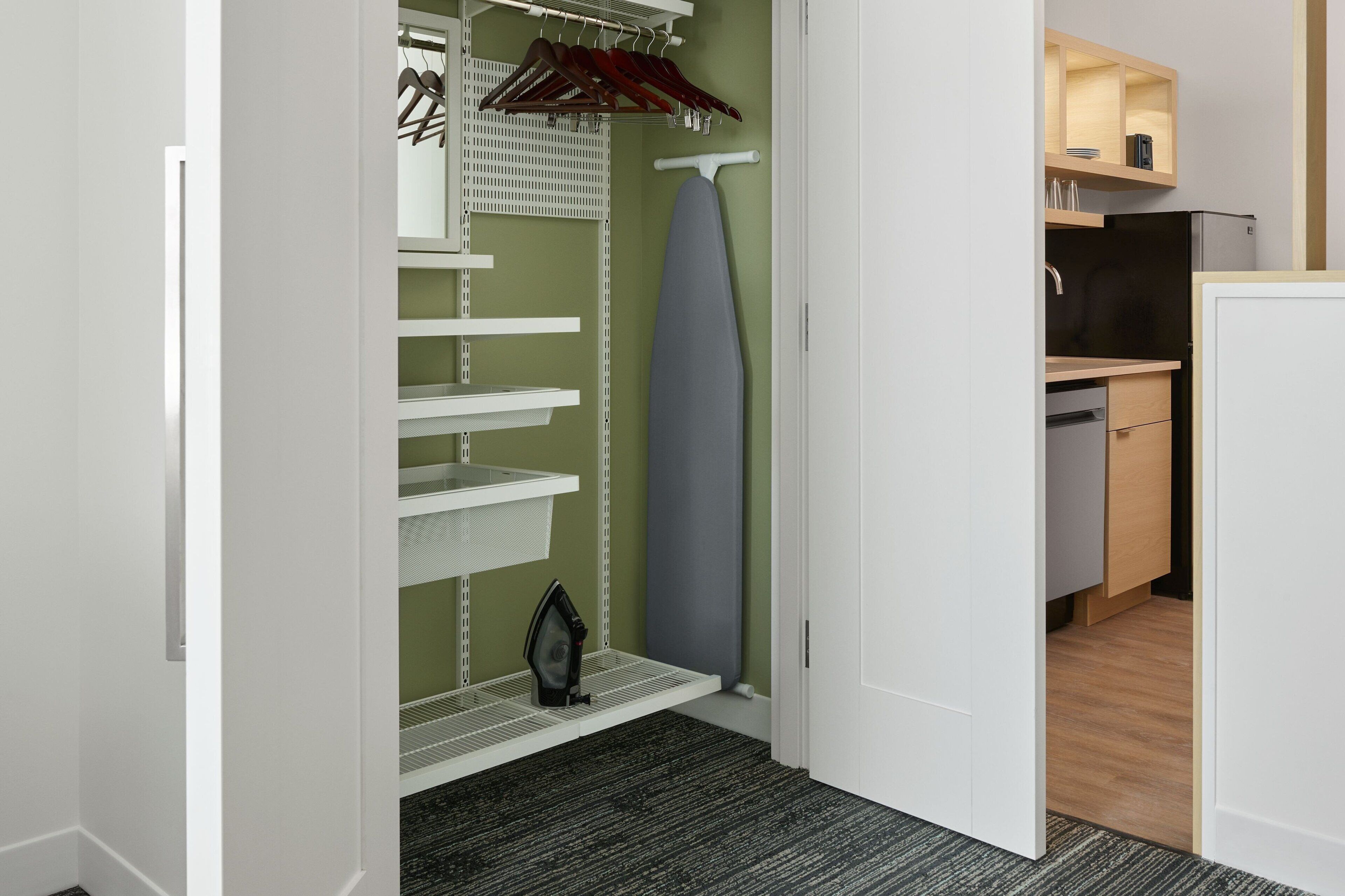 Quarto compacto com roupeiro, tábua de passar e cozinha compacta.