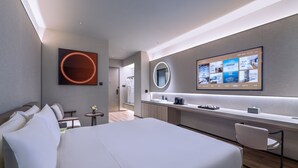 Quarto de hotel moderno com uma cama grande, uma escrivaninha e uma TV exibindo os serviços do quarto.