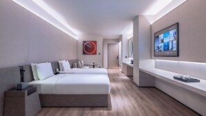 Quarto de hotel moderno com uma cama grande, mesas de cabeceira, uma pequena mesa e TV fixada na parede.