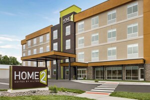 Um hotel de vários andares com design moderno, destacando uma placa grande com a inscrição 'HOME 2 Suites by Hilton'.
