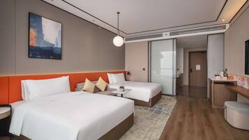 Quarto de hotel moderno com duas camas, um quadro grande, uma escrivaninha e um closet espaçoso.