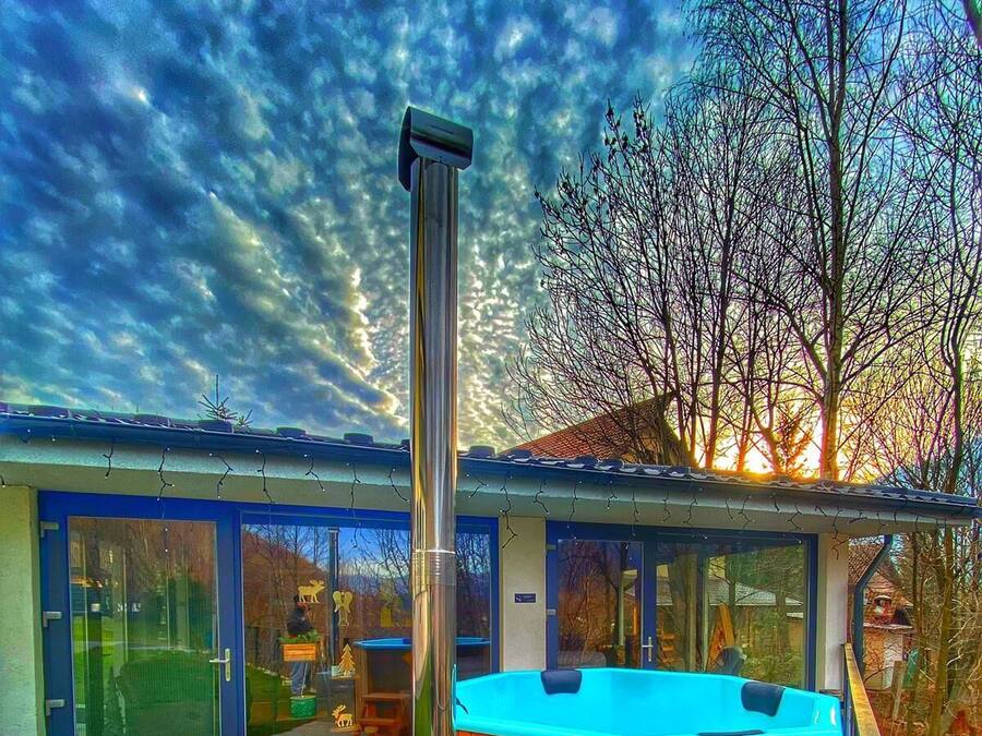 Uma casa moderna com hidromassagem, chaminé e porta de vidro que dá para um deck.