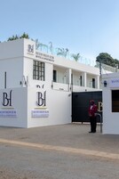 Entrada moderna de hotel, com balcão de recepção e funcionário uniformizado.