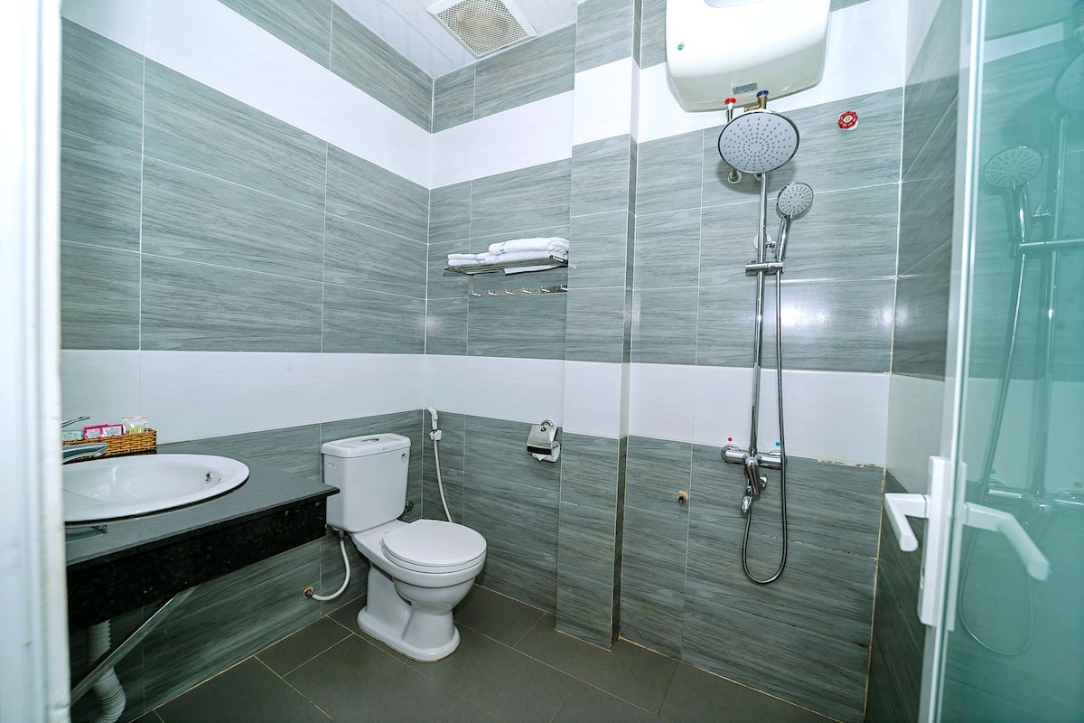 Uma casa de banho moderna com sanita, lavatório e chuveiro.