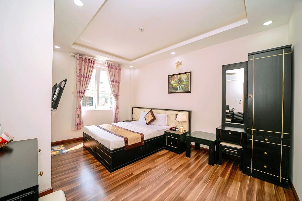 Quarto com cama, mesa de cabeceira, cómoda e espelho.