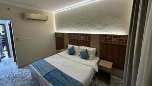 Quarto de hotel com uma cama grande, mesas de cabeceira, ar condicionado e uma cabeceira decorativa.