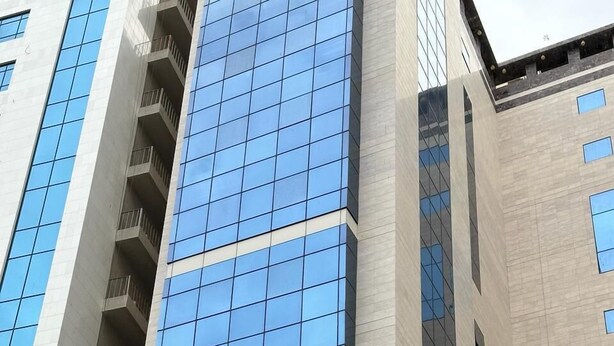 Um edifício moderno com fachada de vidro extensa e placa indicando Hotel Askant Alaziya.