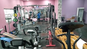 Uma academia com diversos equipamentos de exercício, incluindo esteiras, aparelhos de musculação e pesos livres.