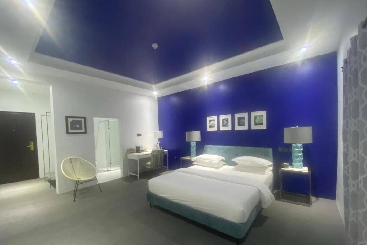 Quarto moderno com uma cama grande, mesas de cabeceira e uma cadeira.