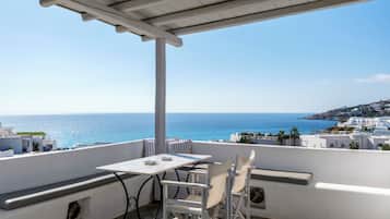 Varanda com mesa e cadeiras com vista para o mar.
