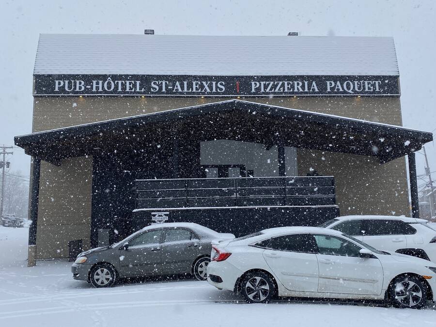 Um edifício com uma placa que diz 'PUB-HOTEL ST-ALEXIS PIZZERIA PAQUET'.