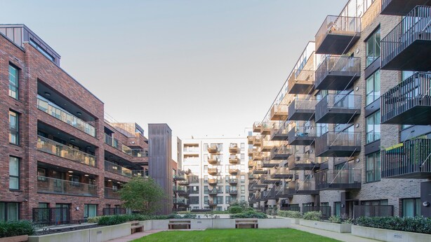 Um edifício de apartamentos moderno com várias varandas e um pátio central.