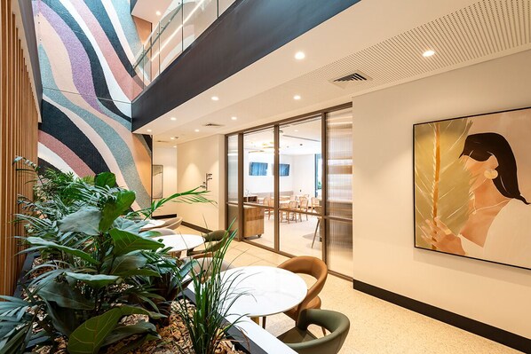 Um espaço interior moderno com design de parede curva, divisória de vidro e área de refeições com cadeiras e mesas.