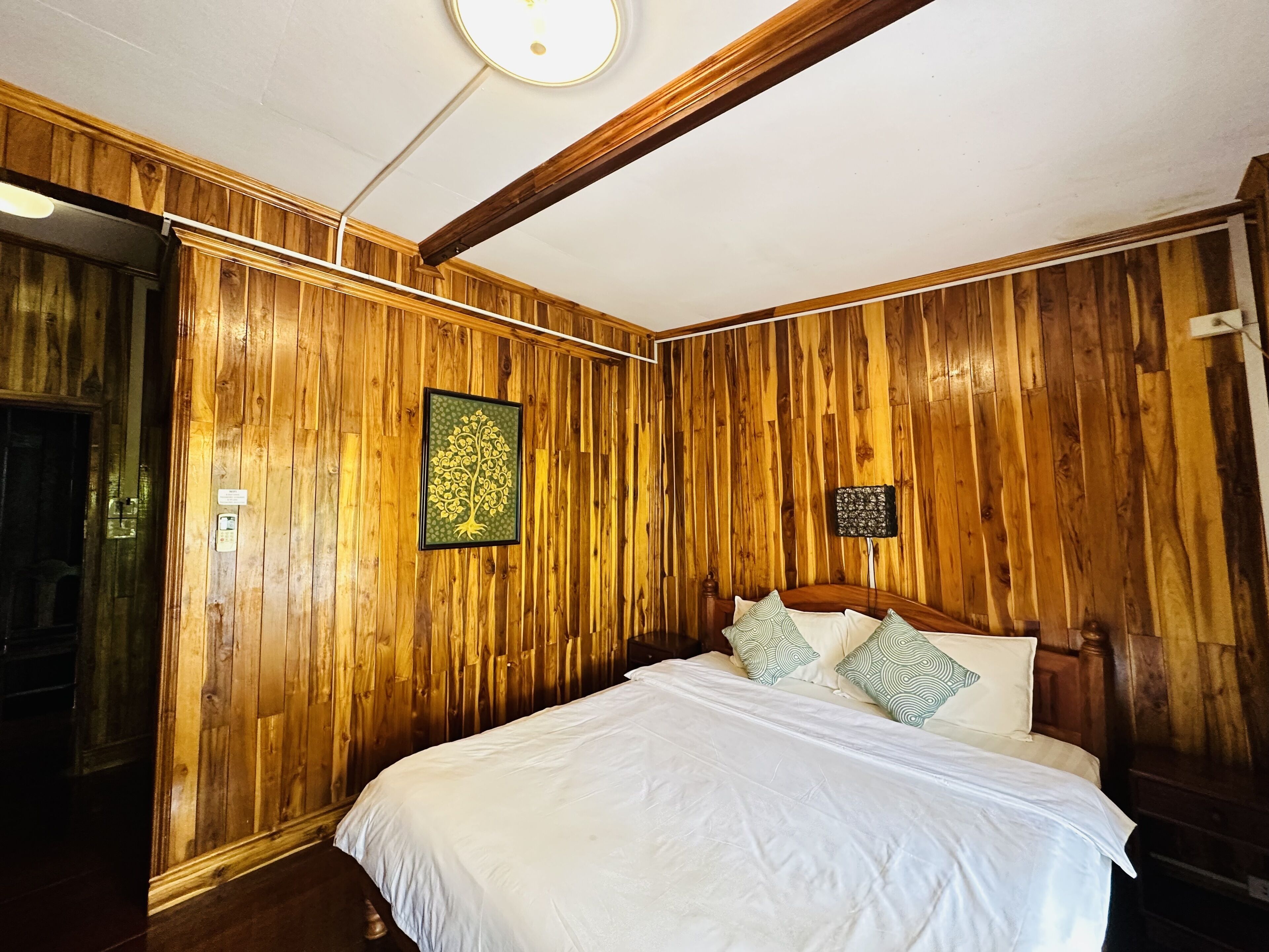 Quarto com painéis de madeira, cama, quadro emoldurado e mesa de cabeceira.