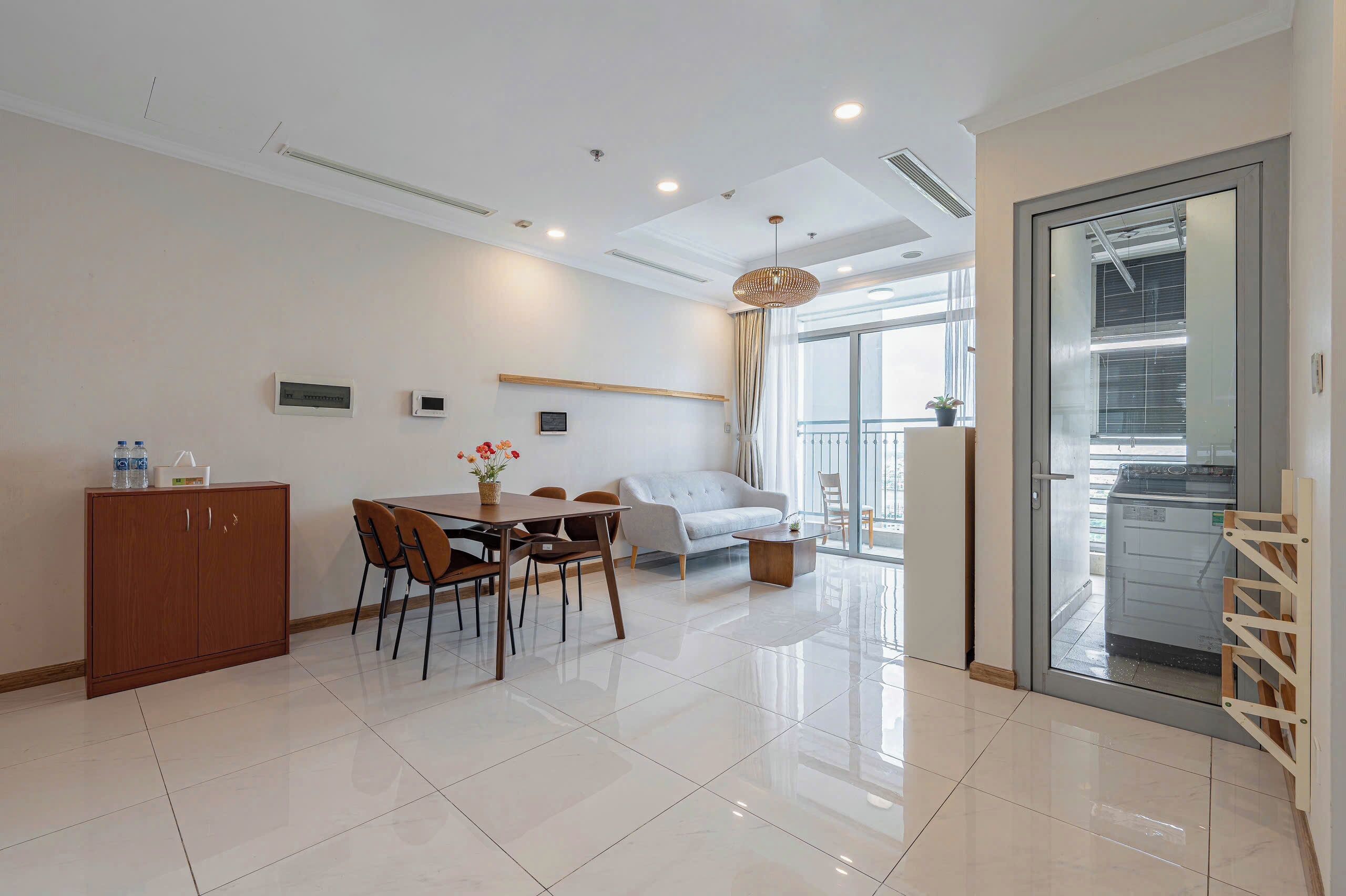 Uma sala de estar moderna com área de jantar, sofá e porta de vidro que dá para uma varanda.