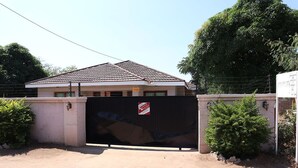 Um condomínio residencial murado, com telhado em azulejo, muro de concreto e um grande portão preto.