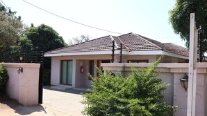 Uma casa residencial com telhado ladrilhado, portão e um pequeno jardim.