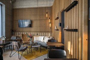 Uma sala de estar moderna com sofá, poltronas, mesa de centro e televisão na parede.
