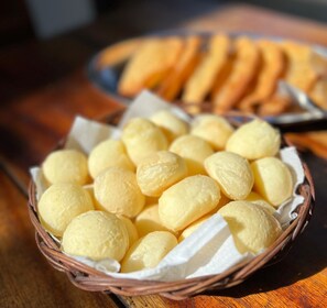 Uma cesta com pães de forma amarelos sobre uma mesa de madeira.