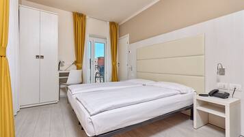 Quarto de hotel com cama, mesa de cabeceira, guarda-roupa e vista para o exterior.