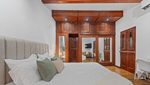 Quarto com uma cama grande, guarda-roupa de madeira e uma escrivaninha.