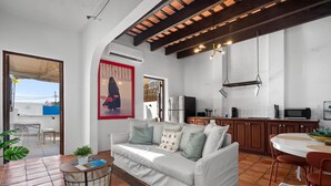 Uma sala de estar moderna com um sofá, uma mesa de jantar e uma área de cozinha.