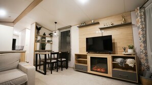 Uma sala de estar moderna com televisão, lareira, estantes de madeira e um espaço para refeições.