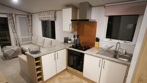 Uma cozinha compacta com forno embutido, pia e bancada pequena.