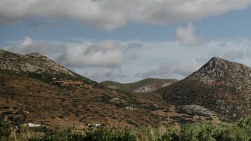 Paisagem montanhosa com céu claro e uma área cercada em primeiro plano.