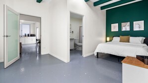 Quarto moderno com cama, mesa de cabeceira e parede verde.