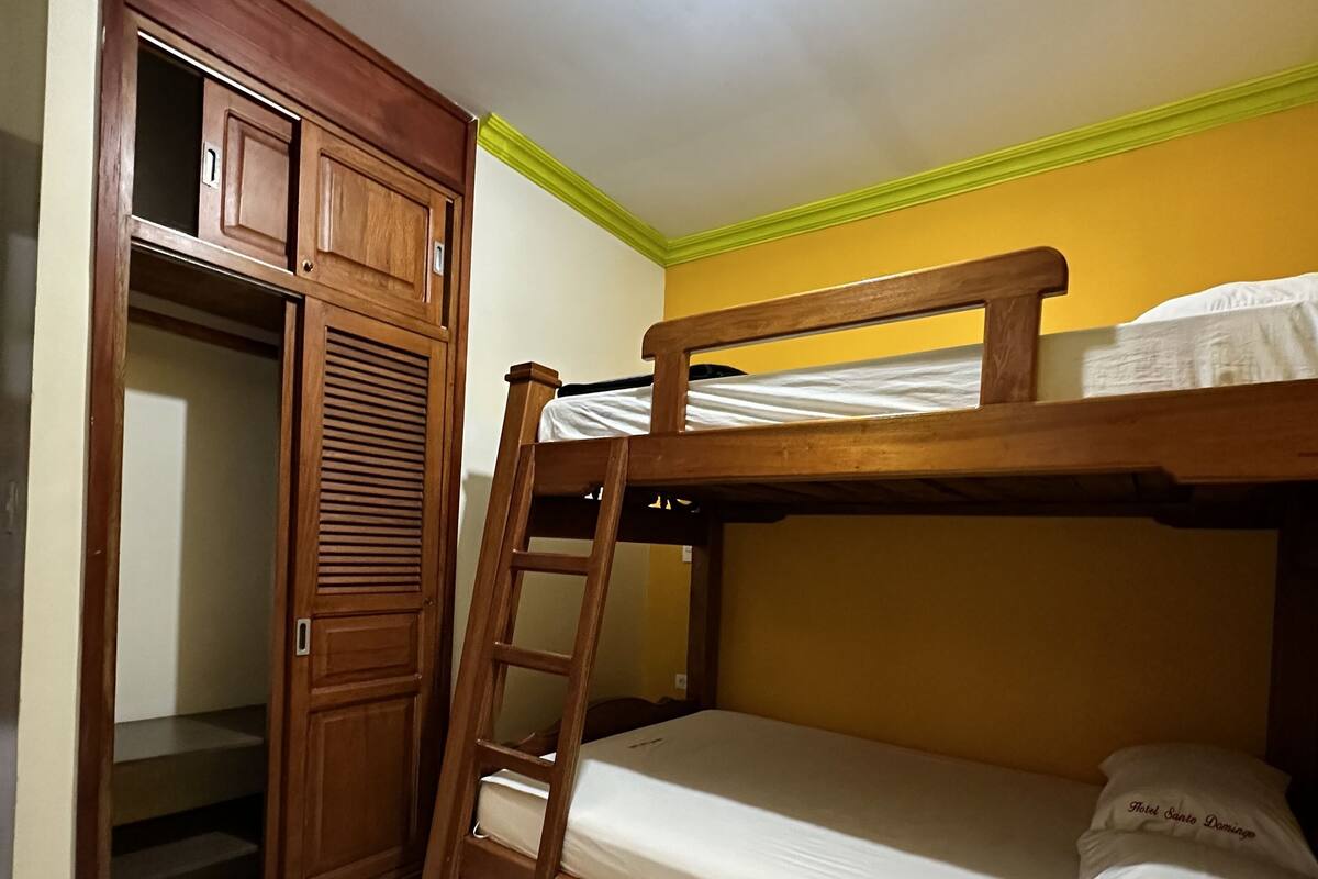 Quarto com beliche, guarda-roupa de madeira e escada.