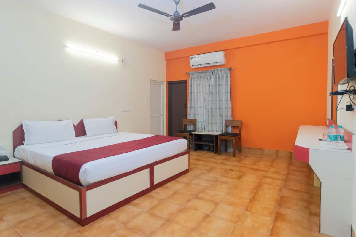 Quarto de hotel com cama, escrivaninha, cadeira, ar condicionado e ventilador de teto.