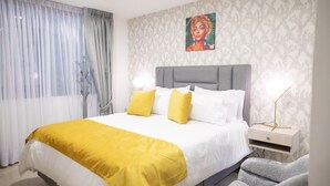 Um quarto com cama, mesa de cabeceira, luminária e cadeira.
