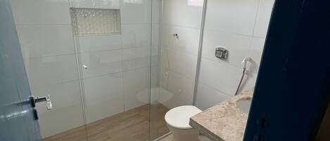 Um banheiro moderno com box de vidro, vaso sanitário e bancada de mármore.
